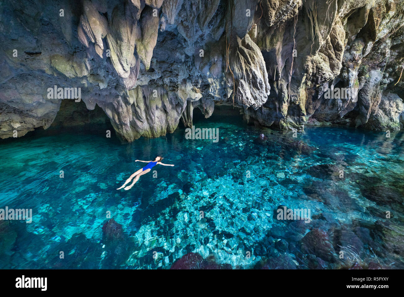 Woman swimming in natural lake inside cave. Colorful reflection ...