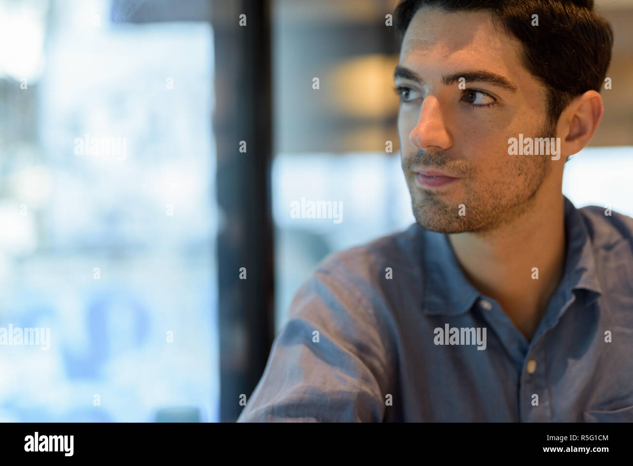 Man sitting and looking through window while thinking Stock Photo - Alamy
