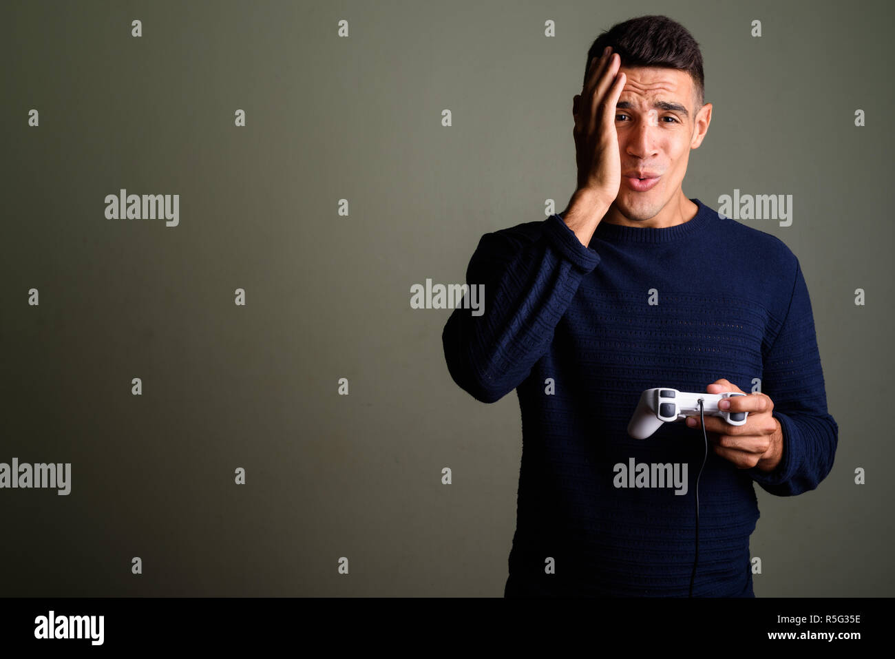 Sad man playing video games with game controller against colored ...