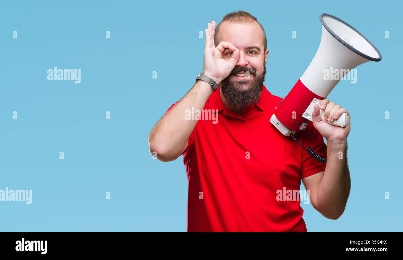Young caucasian man shouting through megaphone over isolated background ...