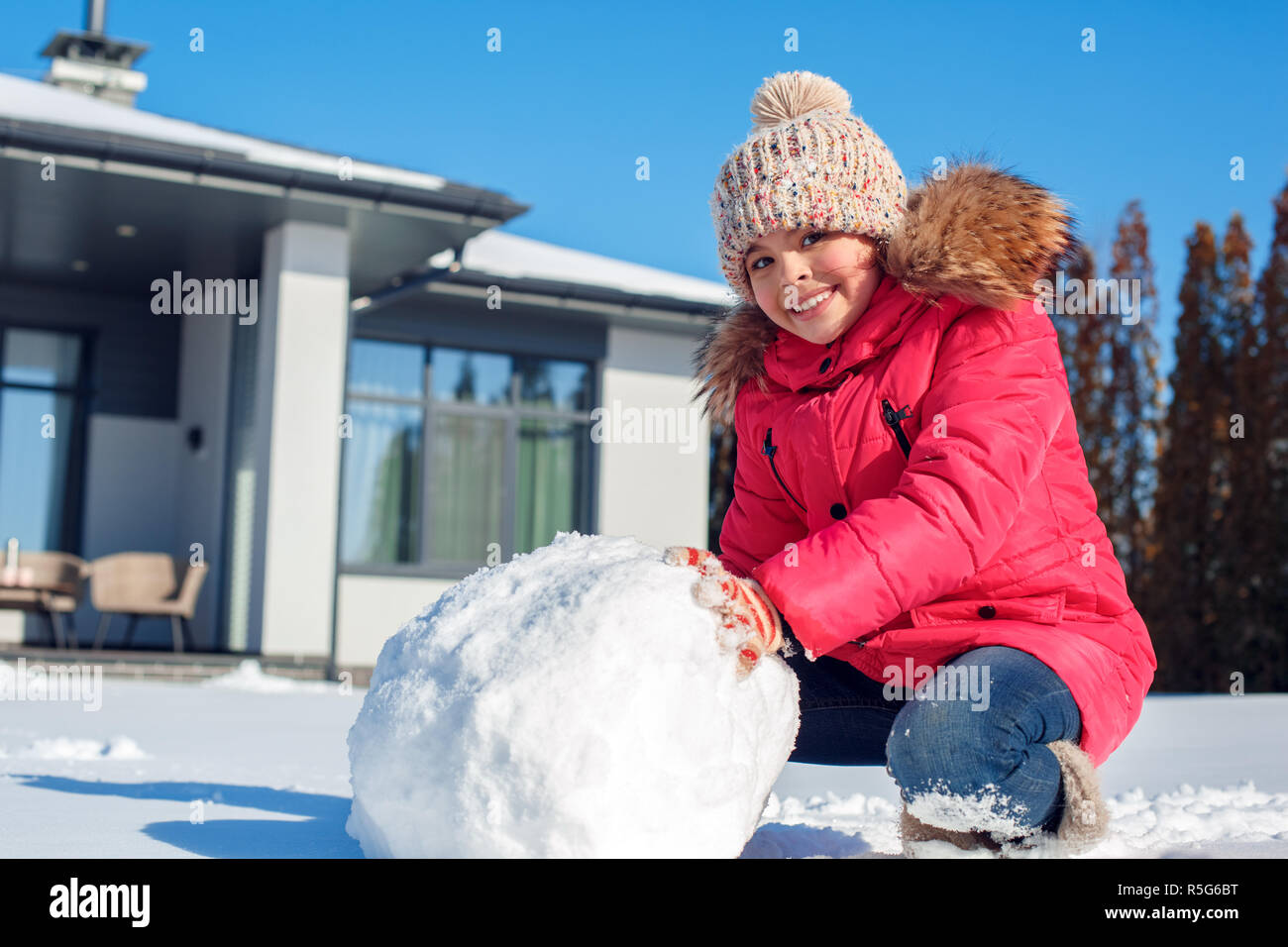 Winter vacation. Girl standing outdoors near house sitting rolling ...