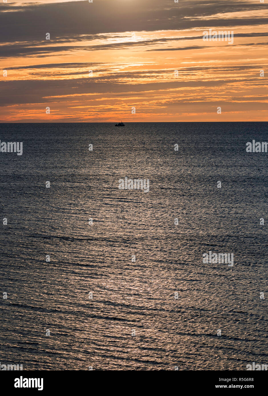 Single Boat on Ocean at Sunset Stock Photo - Alamy