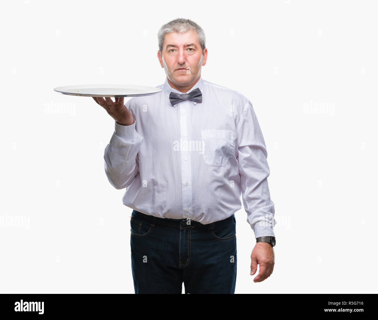 Handsome senior waiter man holding silver tray over isolated background ...