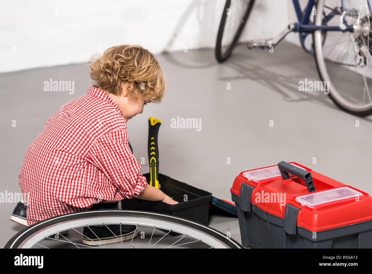 rear view of cute little child sitting near tools box at workshop Stock ...