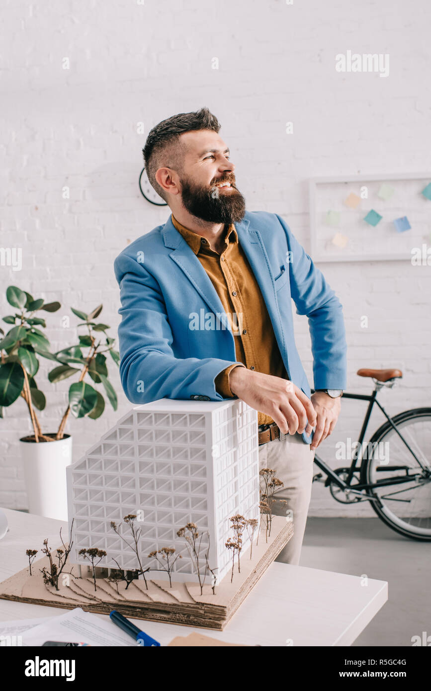 happy adult male architect in formal wear standing near house model in ...