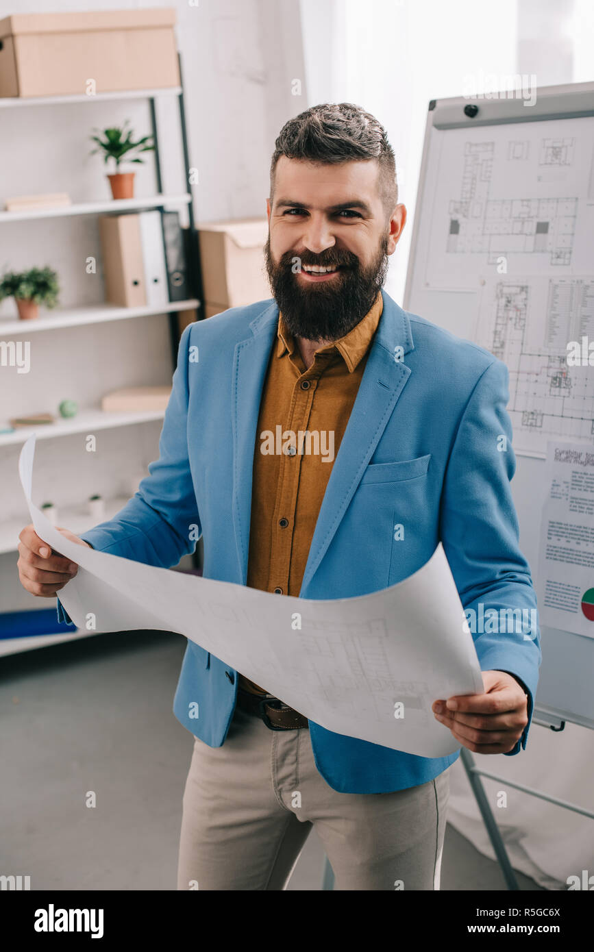 Handsome architect smiling and holding blueprint in modern office Stock ...