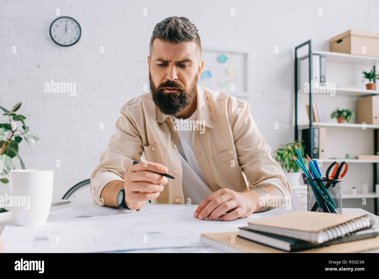 Bearded architect working on blueprints in modern office Stock Photo ...