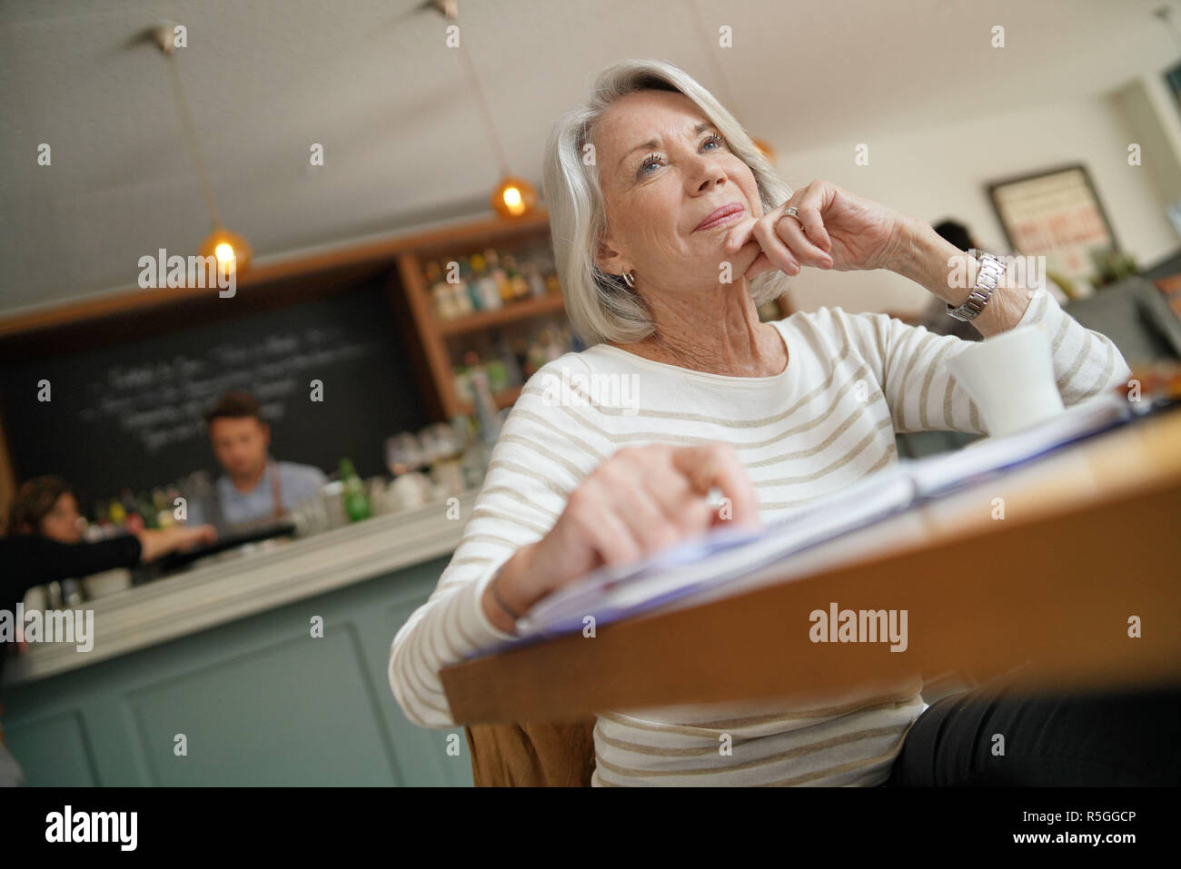 Senior woman looking pensive in a restaurant Stock Photo - Alamy