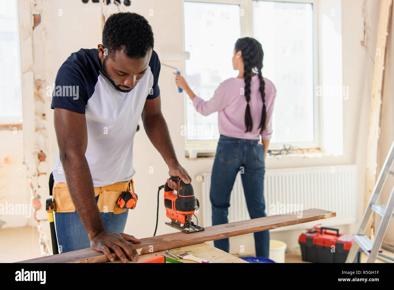 handsome african american man working with jigsaw while his girlfriend ...