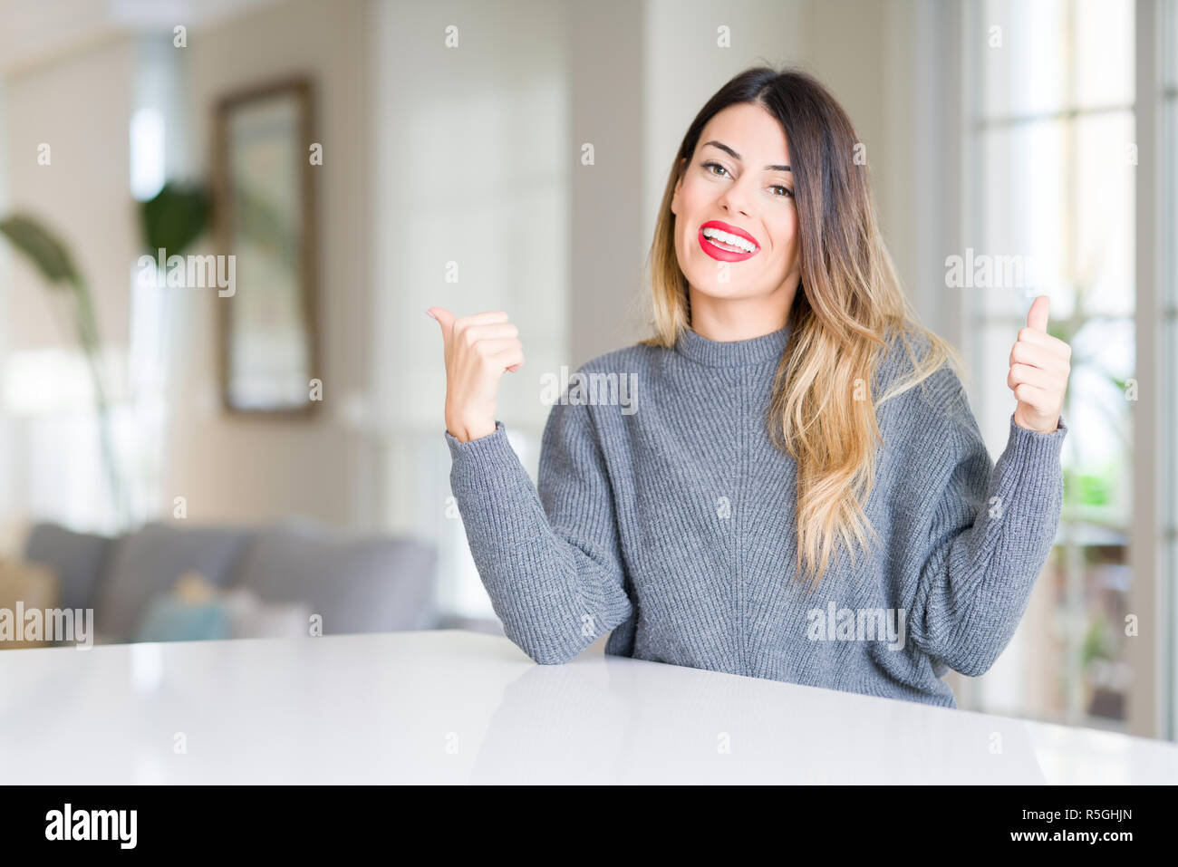 Young beautiful woman wearing winter sweater at home success sign doing ...