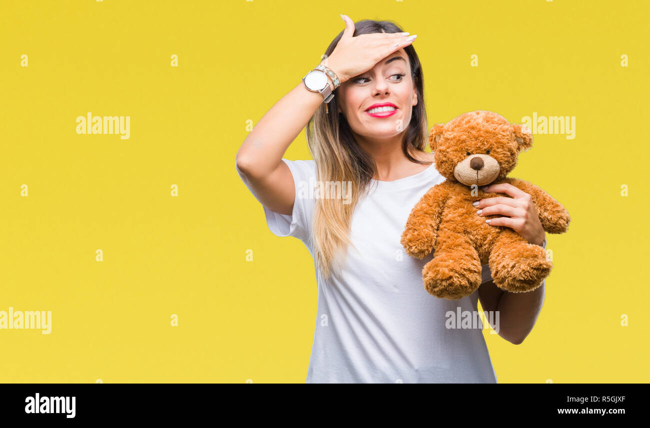 Young beautiful woman holding teddy bear plush over isolated background ...