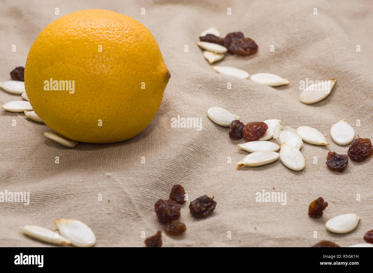 Pumpkin seeds, lemon and raisins scattered on canvas background Stock ...