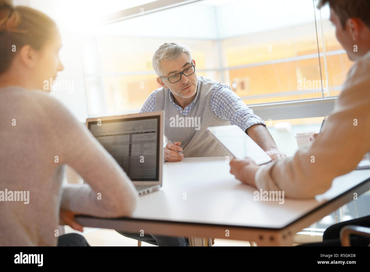 Teacher meeting around table with students Stock Photo - Alamy