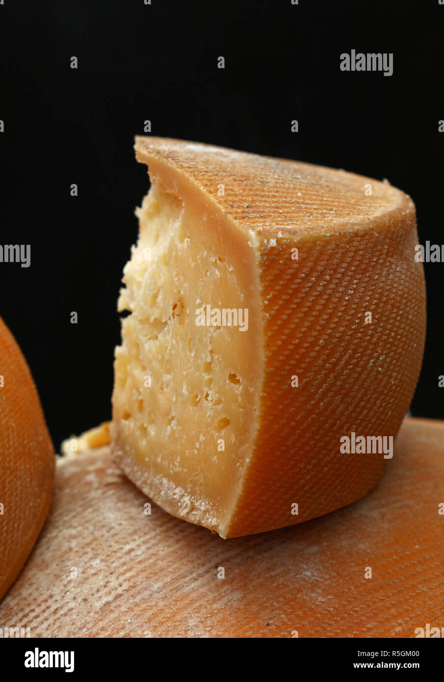 Cut block of aged cheese over black background Stock Photo - Alamy