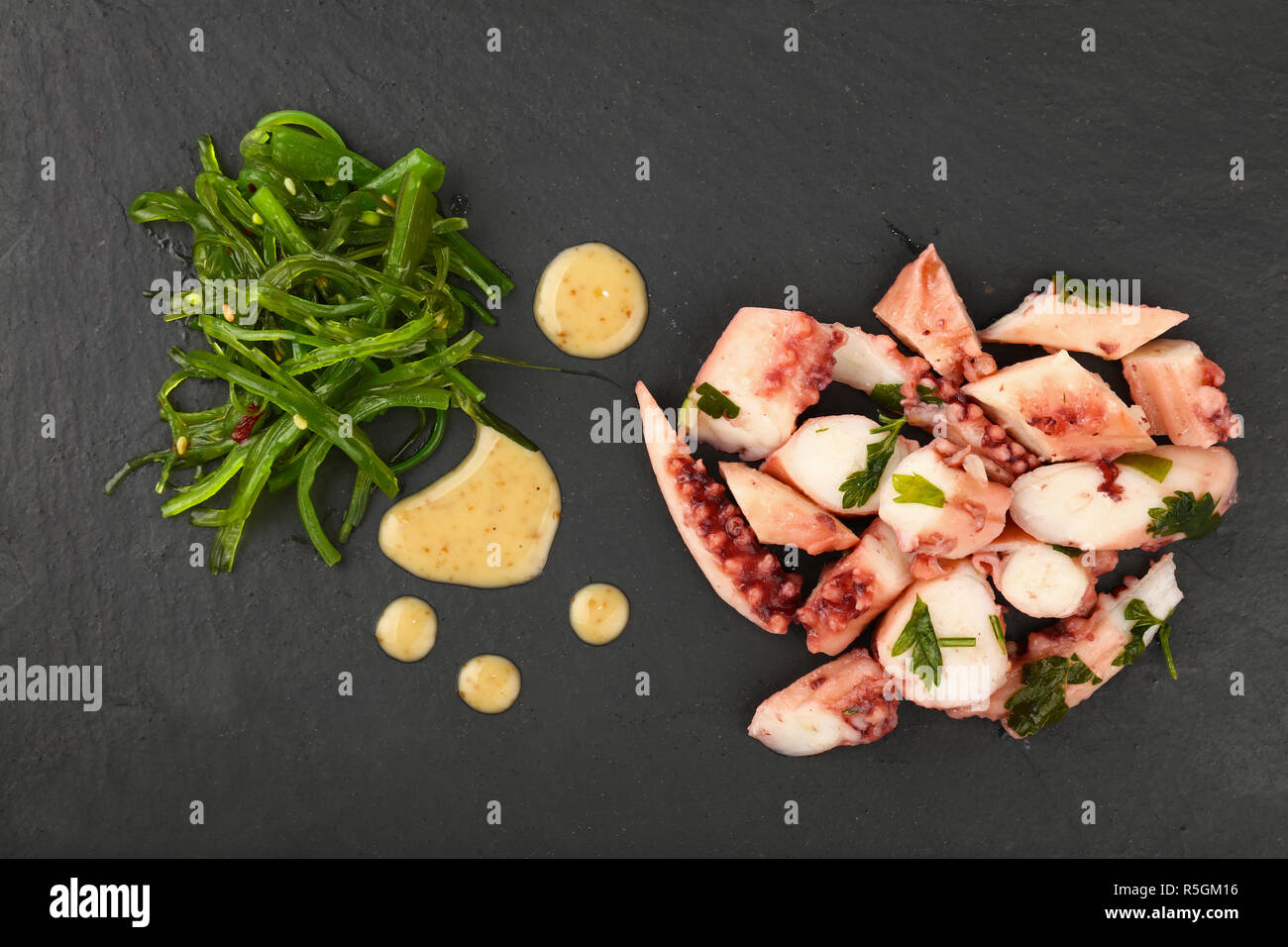 Octopus arm slices and seaweed salad on black Stock Photo - Alamy