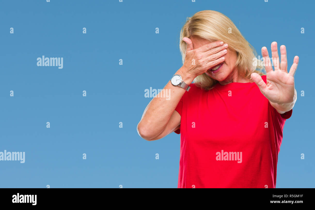 Middle age blonde woman over isolated background covering eyes with ...