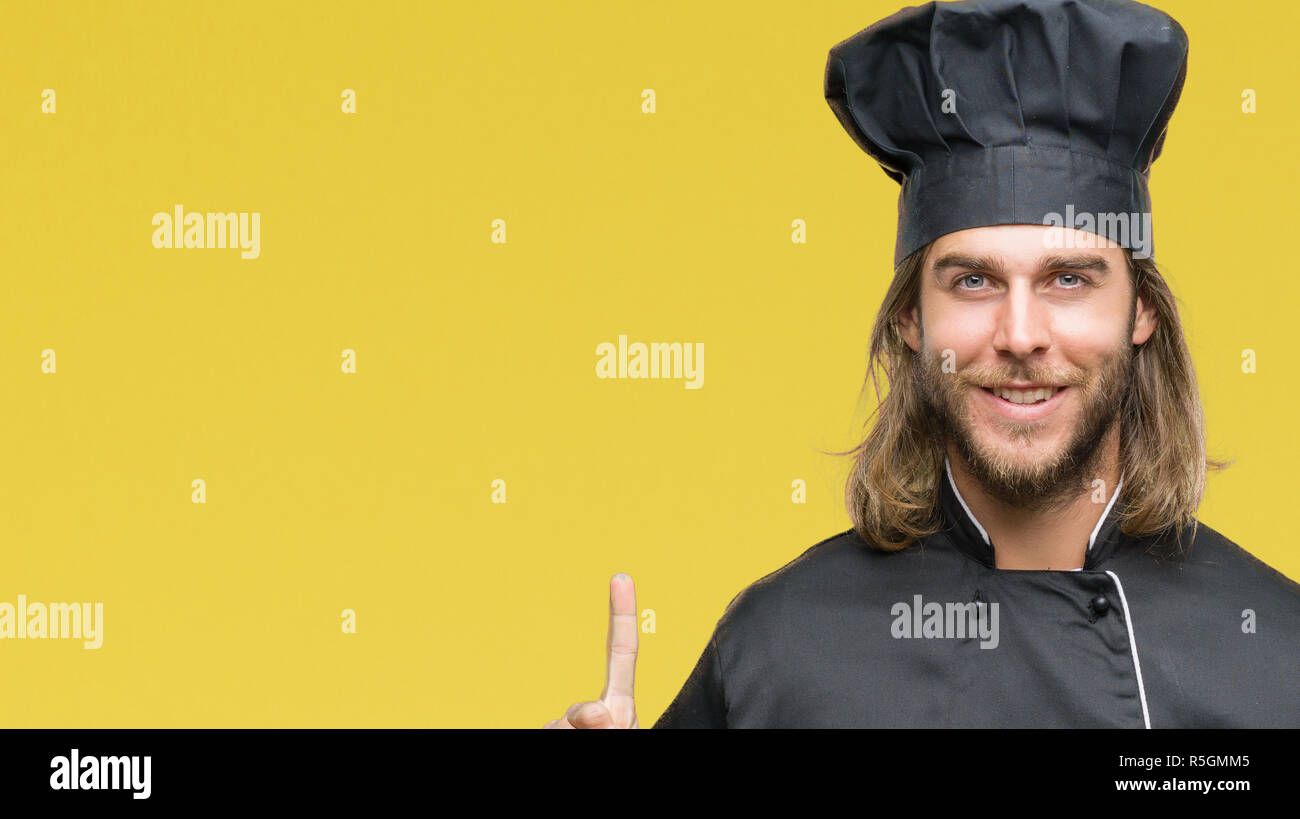 Young handsome cook man with long hair over isolated background showing ...