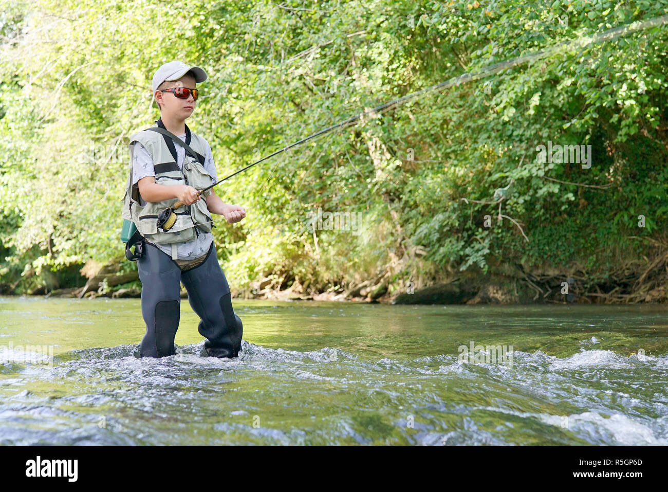 Young boy fly-fishing in river Stock Photo - Alamy