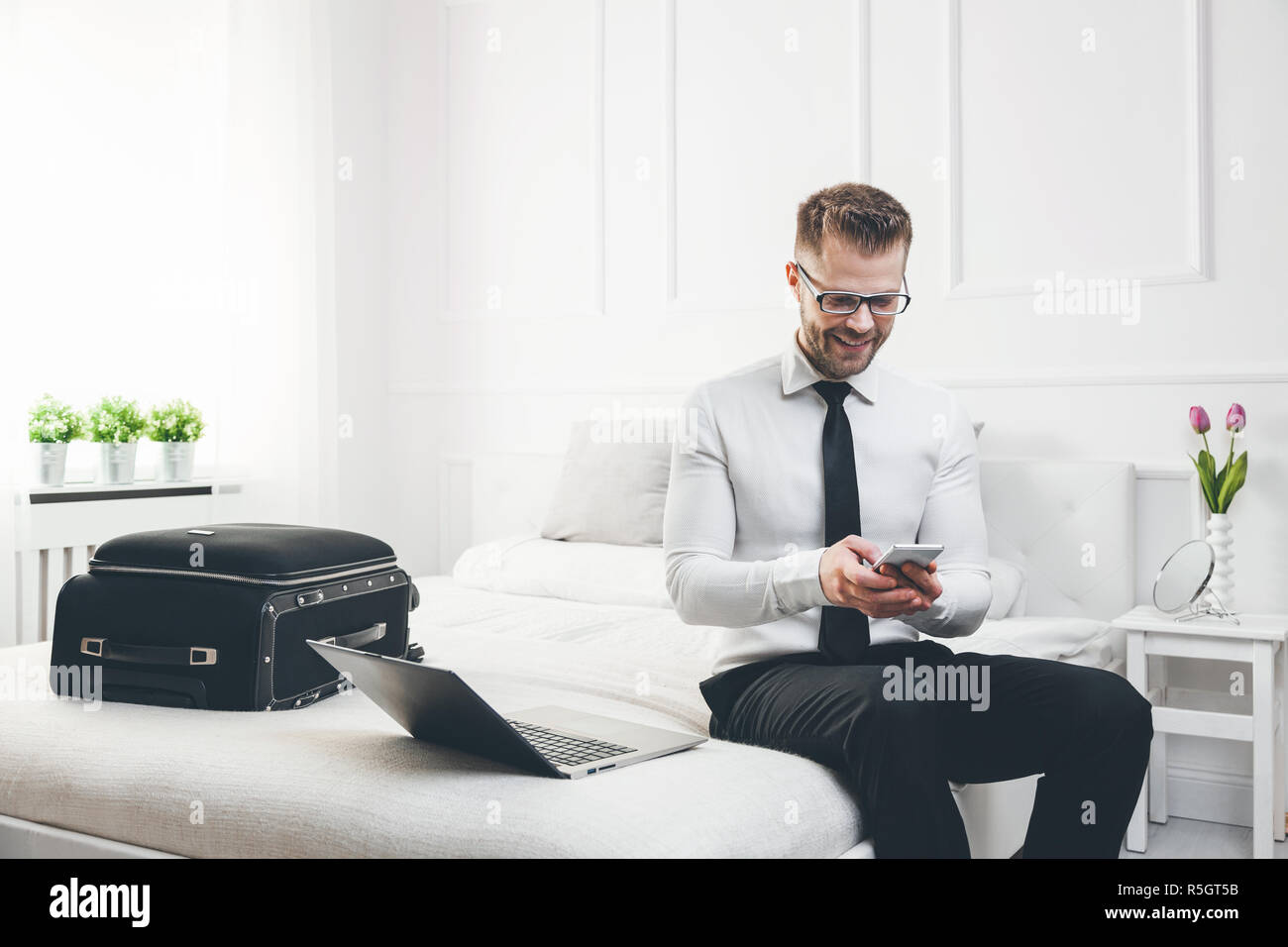 Businessman working from a hotel room with his mobile phone Stock Photo ...
