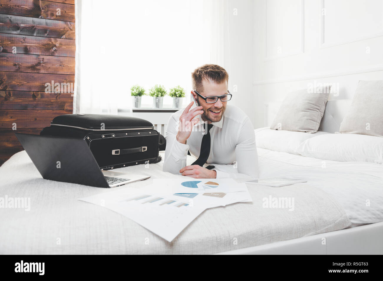 Businessman working from a hotel room with his mobile phone Stock Photo ...
