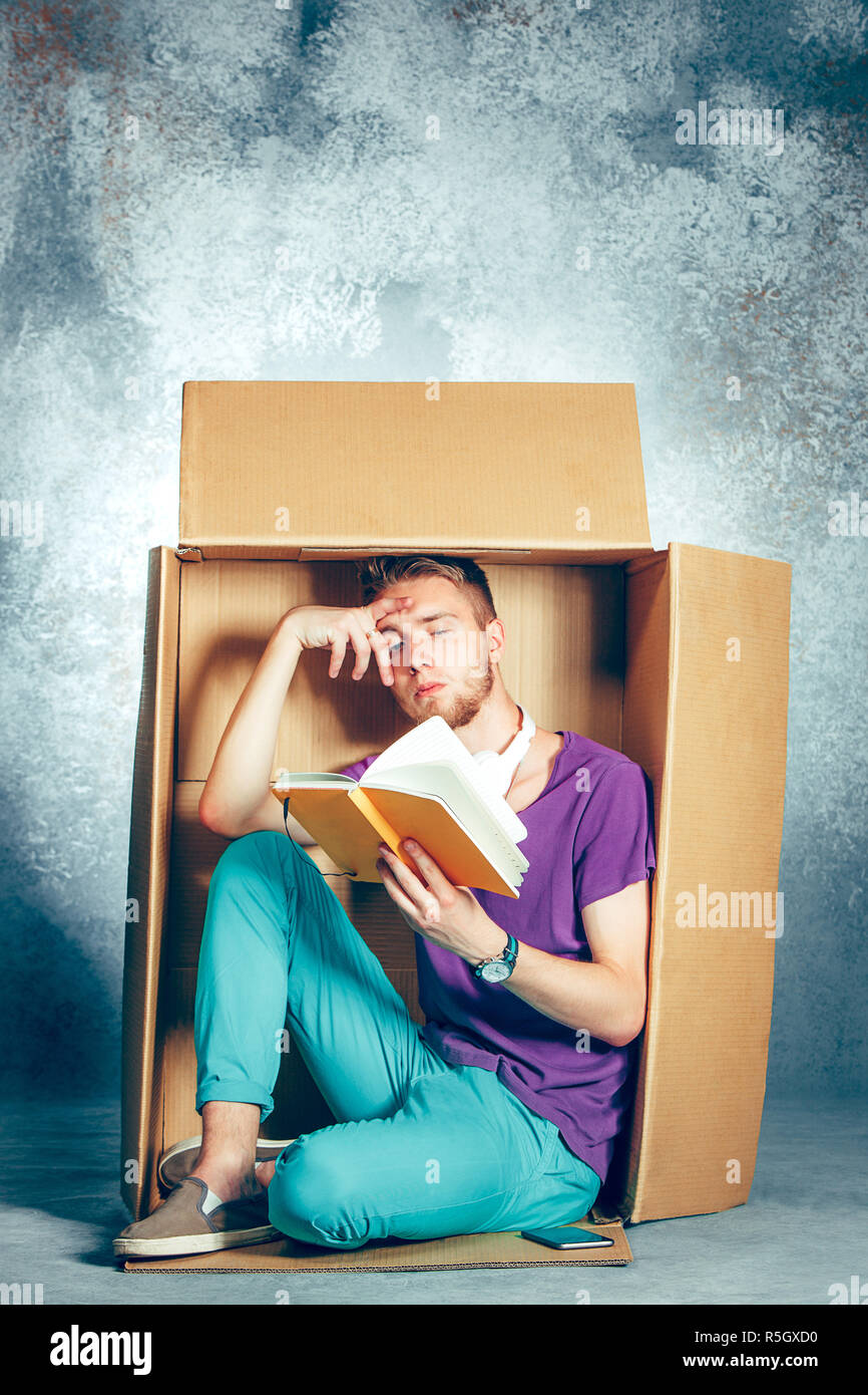 Introvert concept. Man sitting inside box and reading book Stock Photo ...