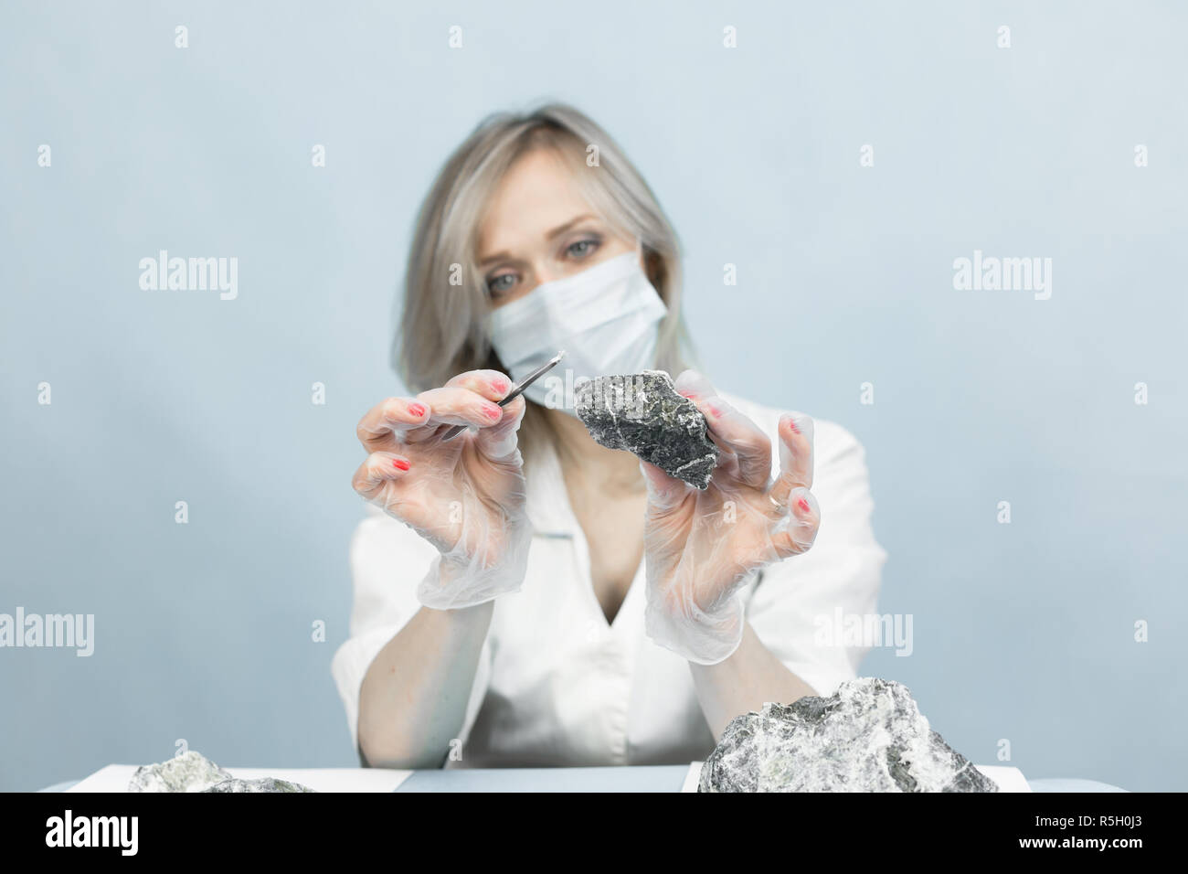 A woman lab worker examines the stones with tweezers takes the fibers ...