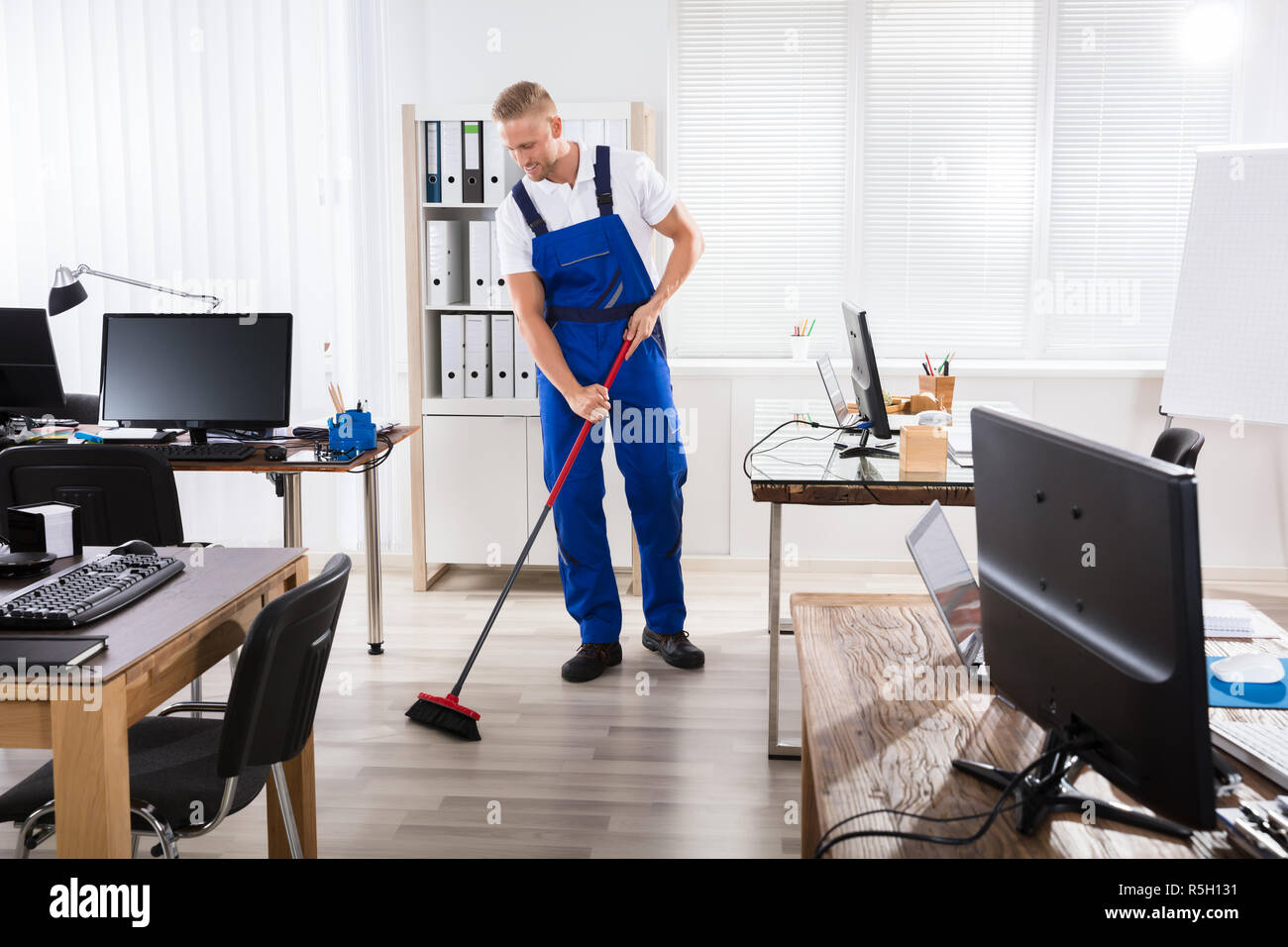 Male Janitor Cleaning Floor With Broom Stock Photo - Alamy