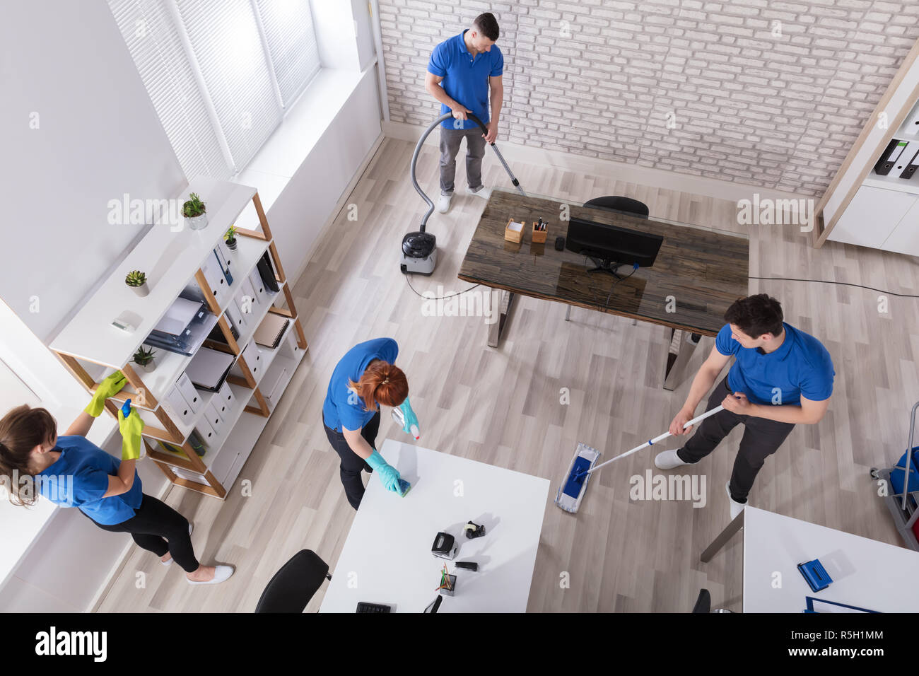 Group Of Janitors Cleaning The Office Stock Photo - Alamy