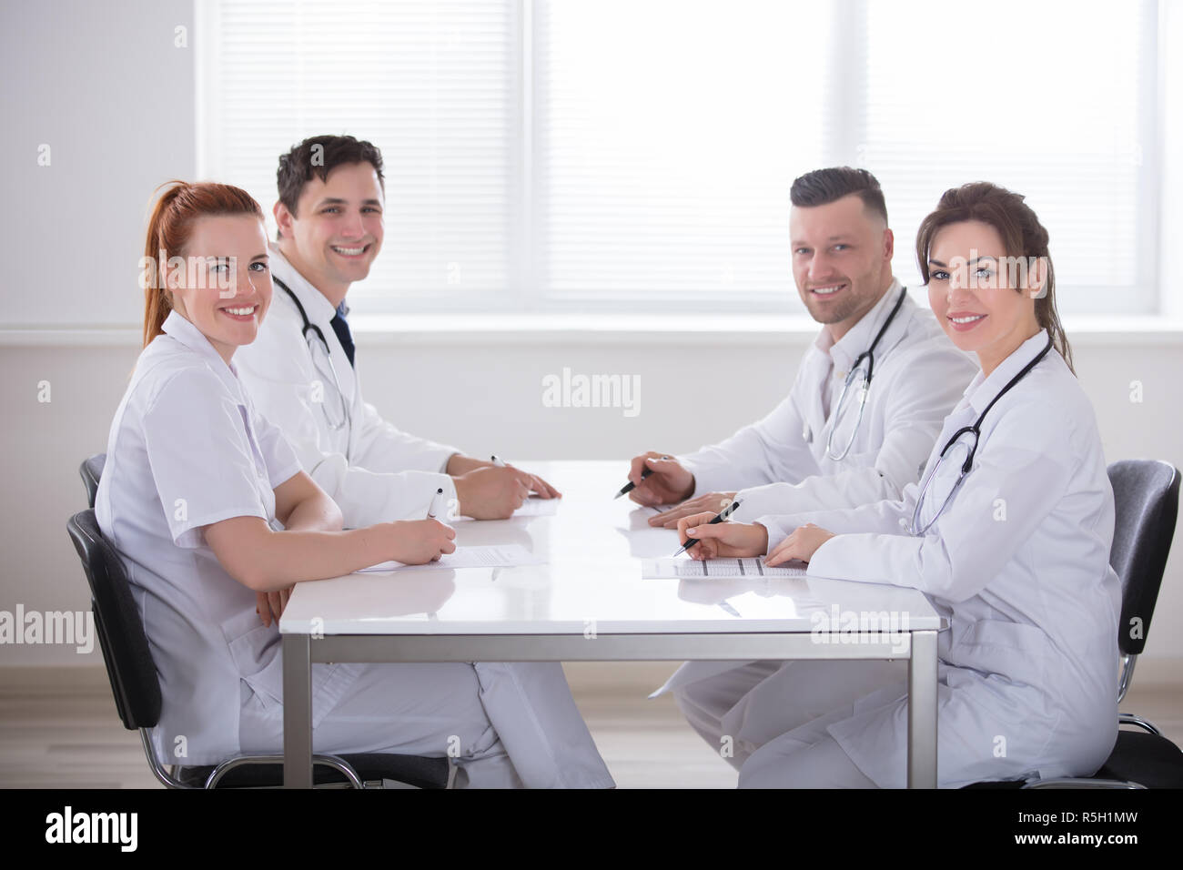 Happy Doctors Sitting Together Stock Photo - Alamy