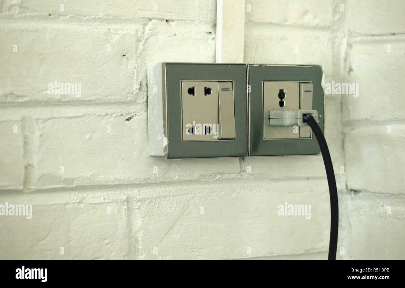 PLUGGED OLD SOCKET ON WHITE BRICK WALL Stock Photo - Alamy
