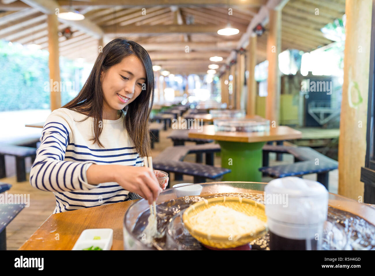 Woman eating japanese cold noodles with water flow Stock Photo - Alamy