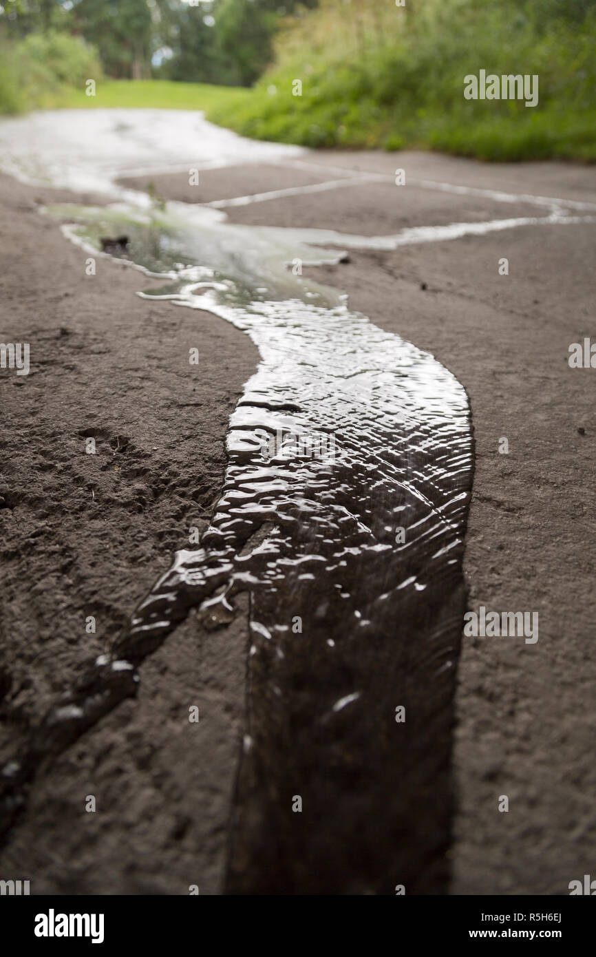 Rainwater Streaming down Asphalt Stock Photo - Alamy