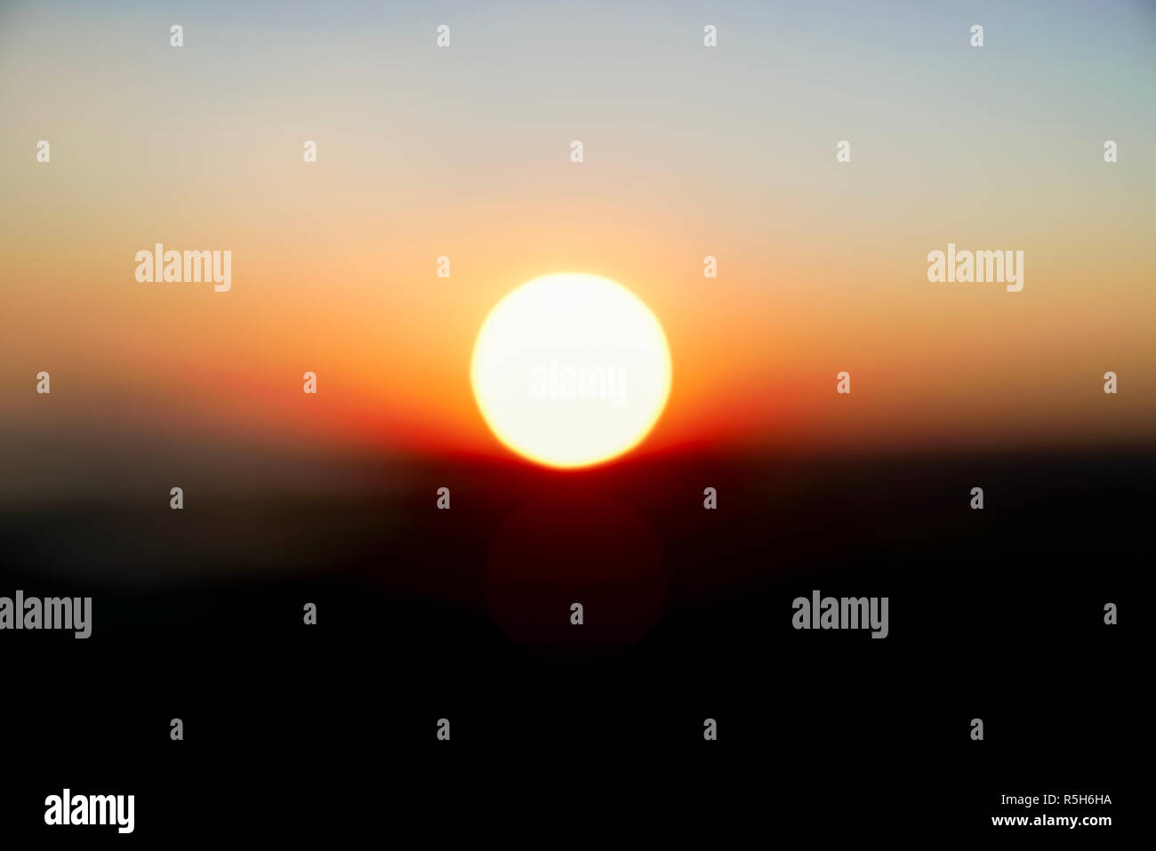 Large golden sun on horizon as sunrises defocused with abstract effect ...