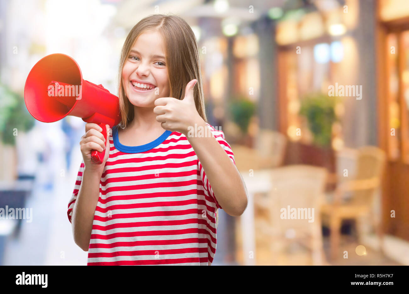 Young beautiful girl yelling through megaphone over isolated background ...
