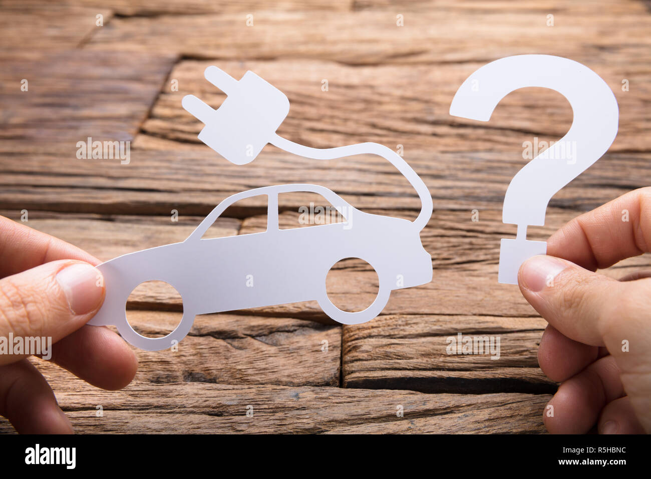Holding Paper Electric Car And Question Mark At Table Stock Photo - Alamy