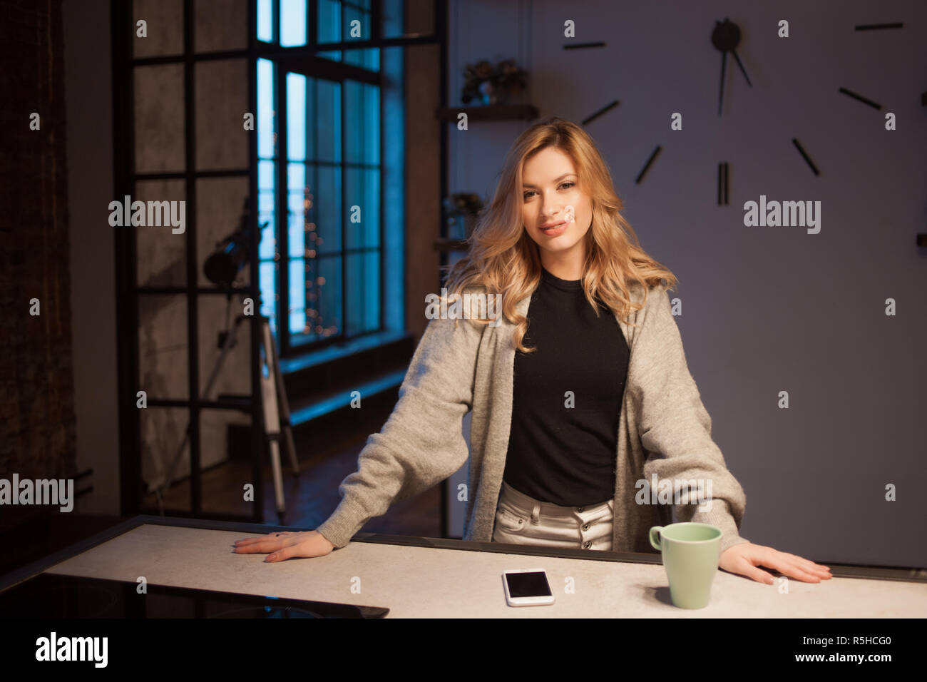 Beautiful young woman in the kitchen, early morning, dark in the ...