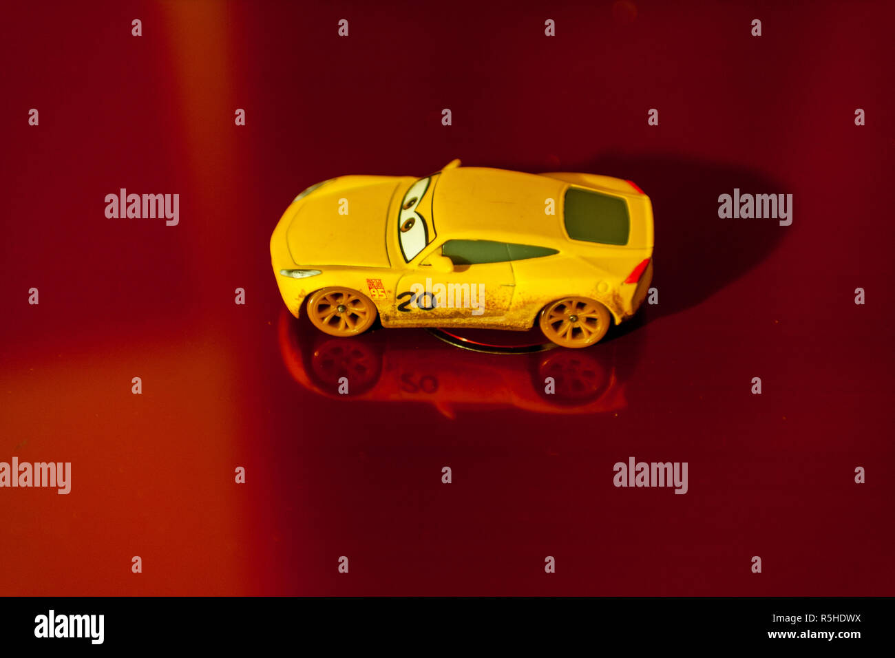 yellow toy car on reflective red surface Stock Photo - Alamy