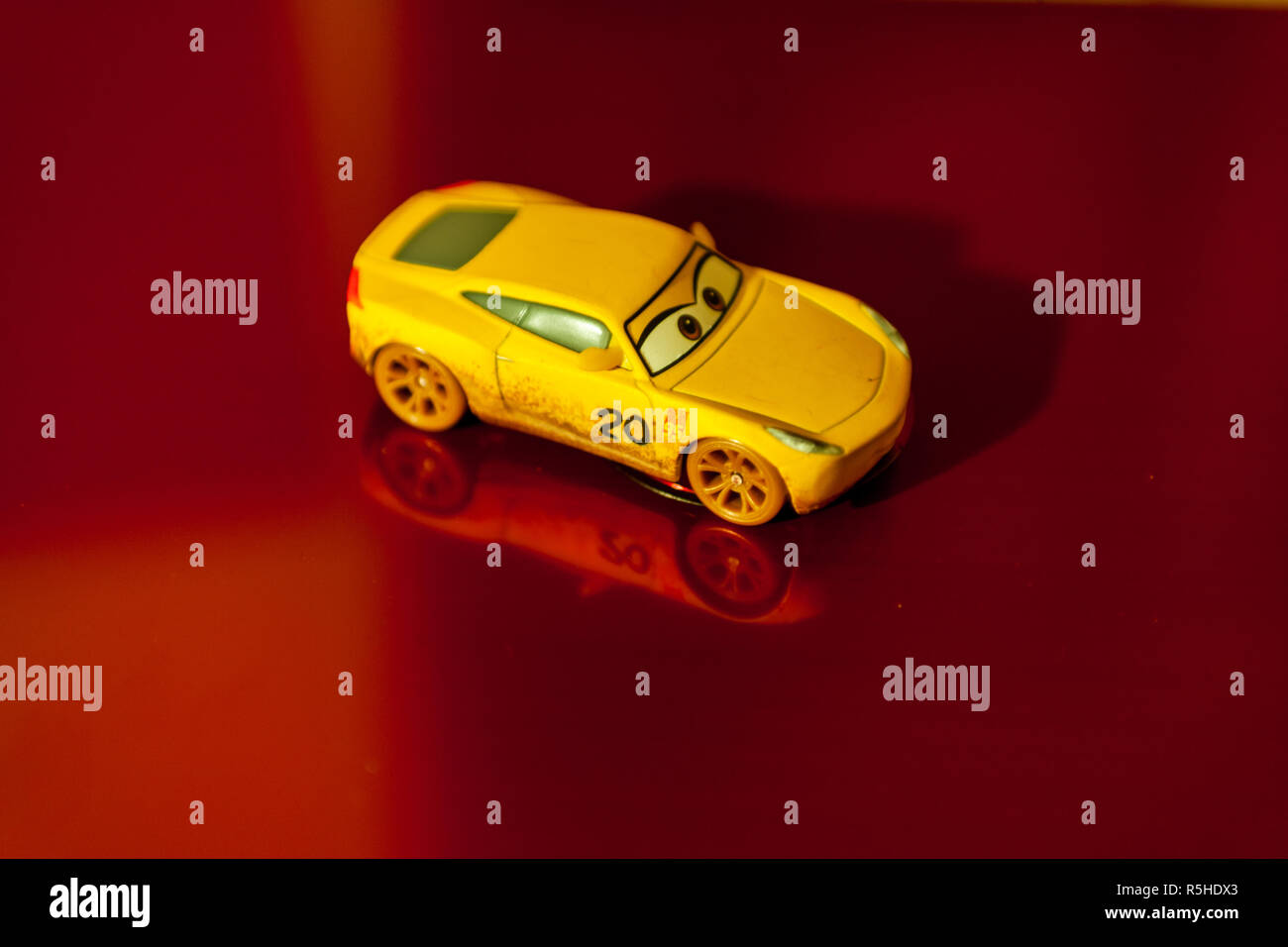 yellow toy car on reflective red surface Stock Photo - Alamy