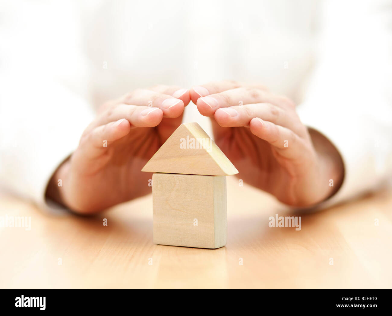 Wooden toy house protected by hands Stock Photo - Alamy