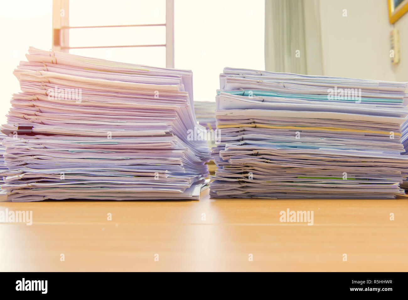 documents on desk stack up high waiting to be managed Stock Photo - Alamy