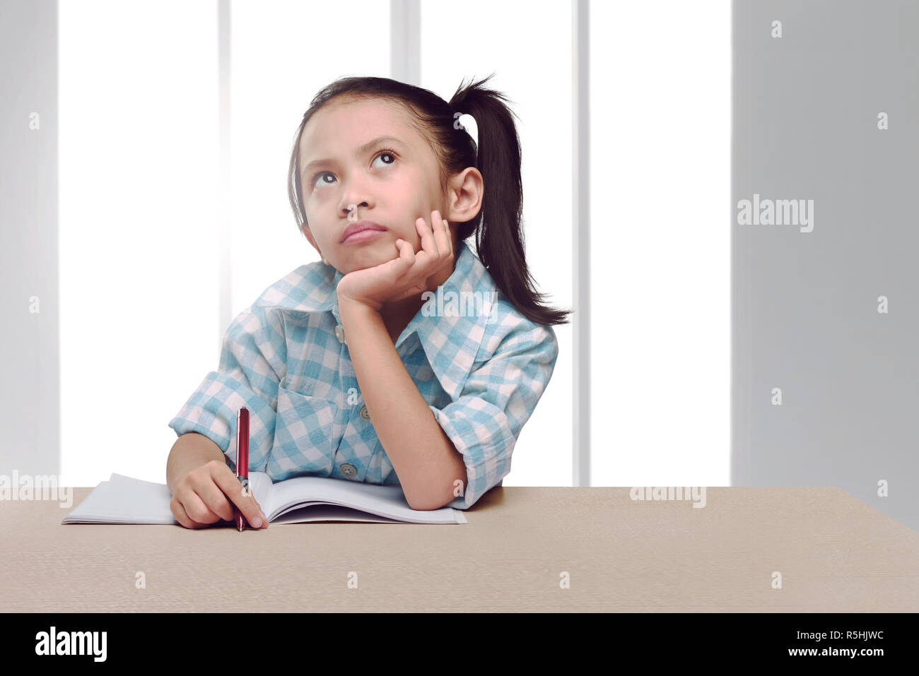 Pretty asian kid doing homework with pen Stock Photo - Alamy