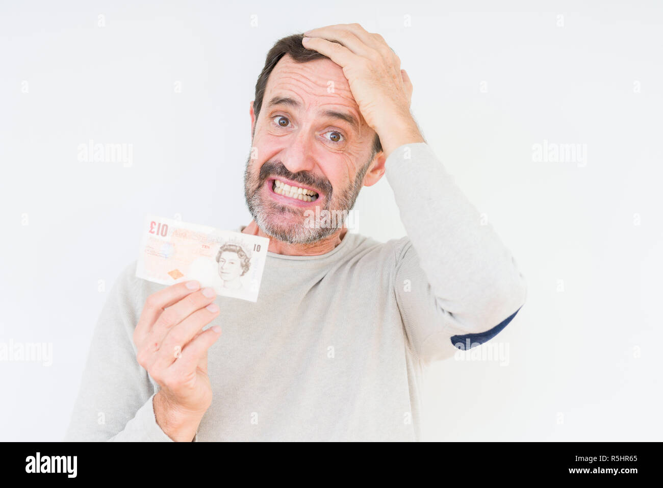 Senior man holding ten pounds bank note over isolated background ...