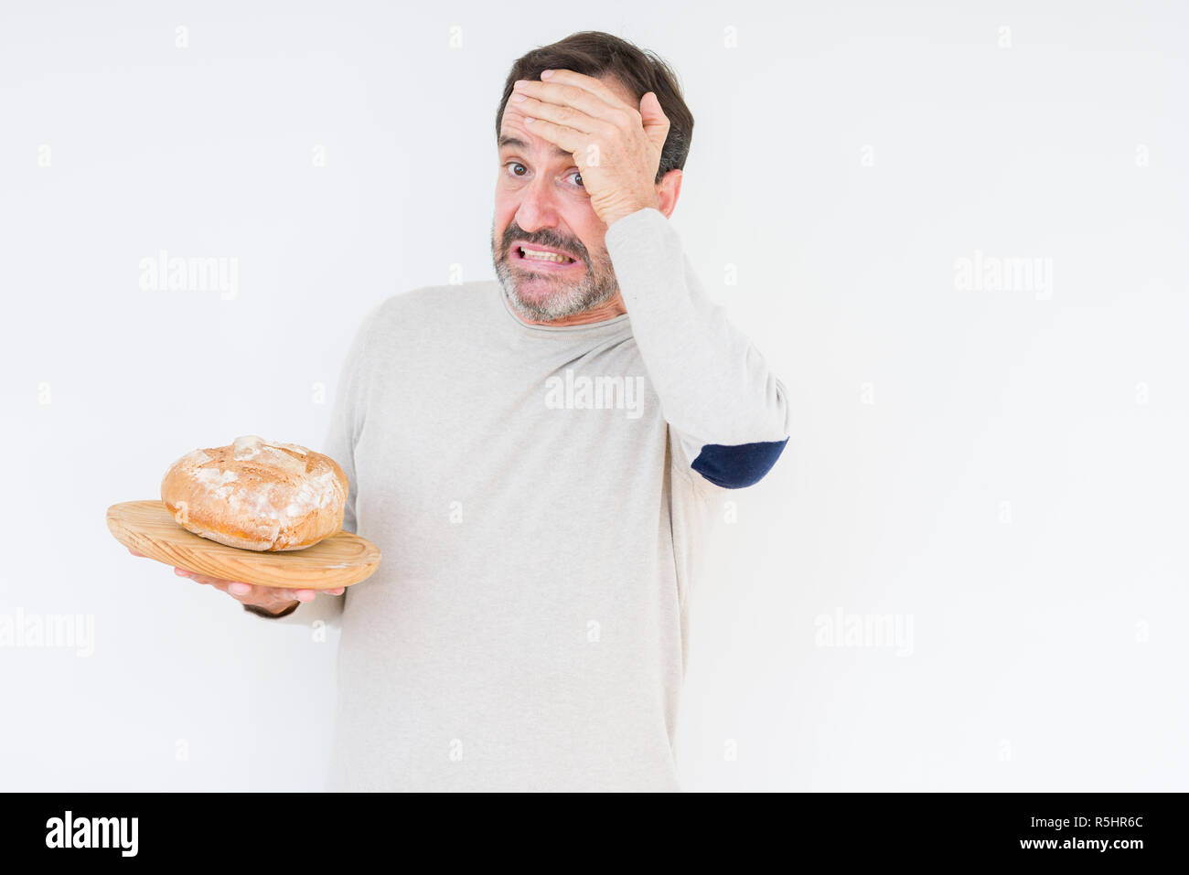 Senior man holding homemade fresh bread over isolated background ...