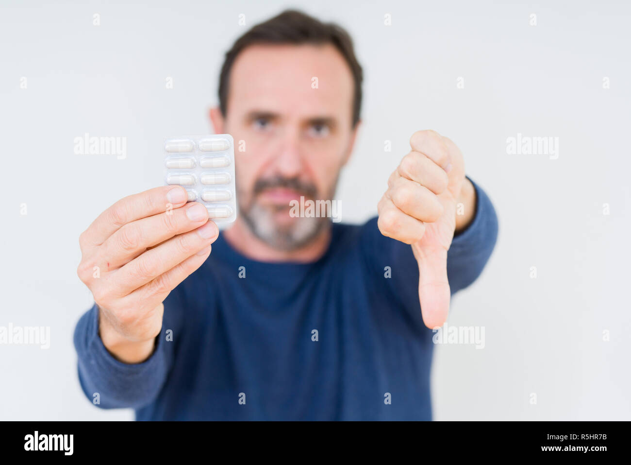 Senior man holding pharmaceutical pills over isolated background with ...