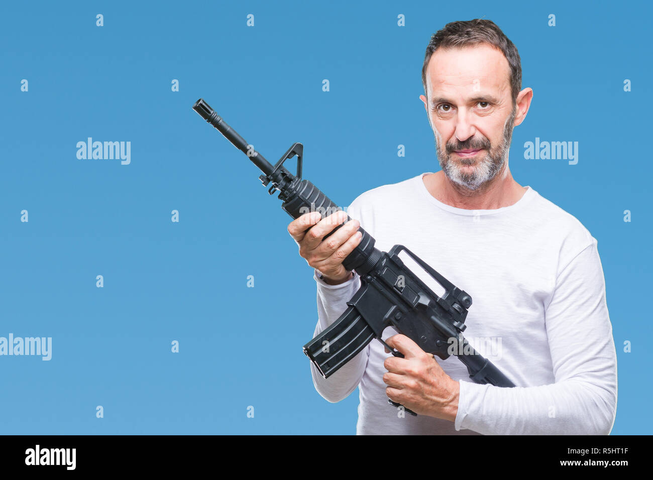 Middle age senior hoary criminal man holding gun weapon over isolated ...