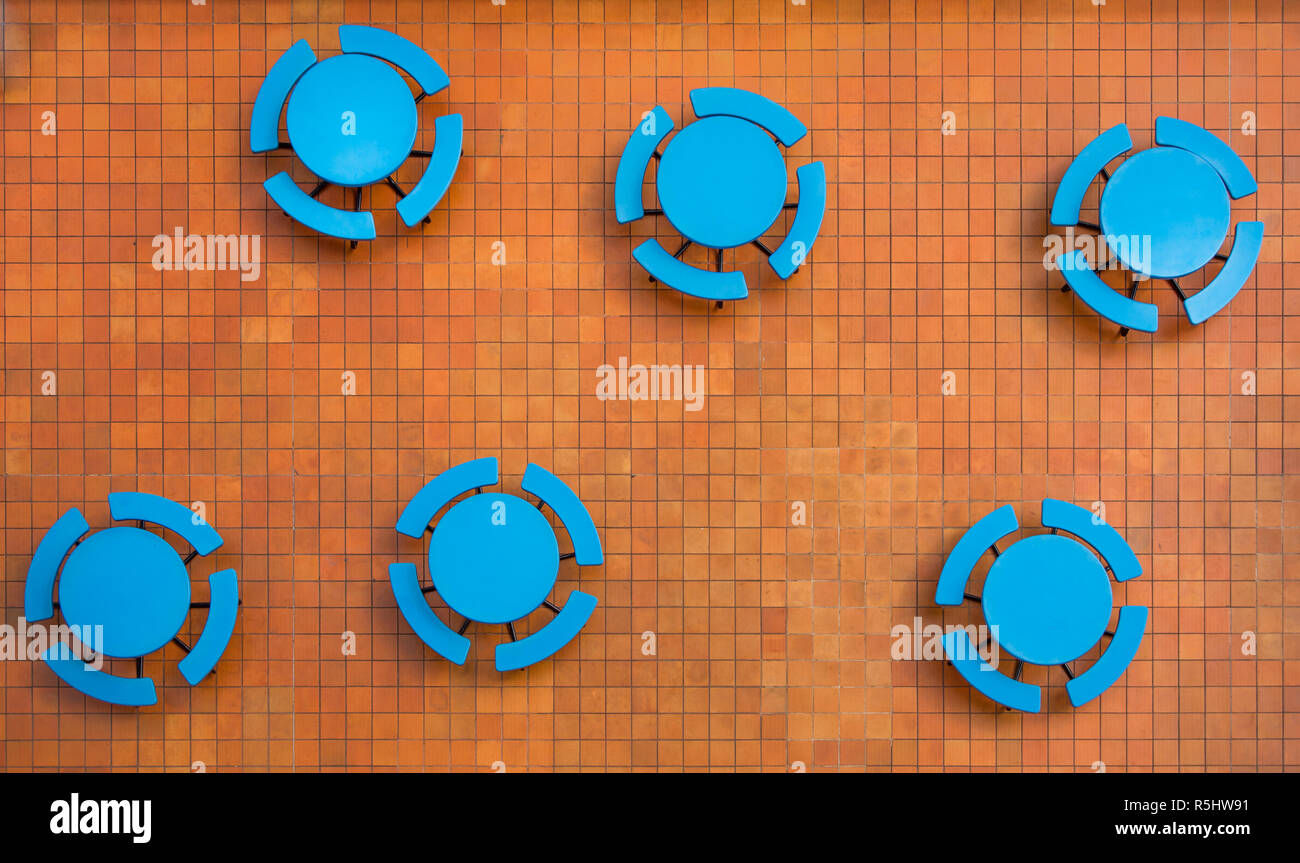 Orange square tile patio and empty, round blue tables in a vacant food ...