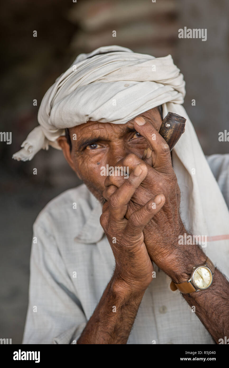 Portrait of an Indian man smoking traditional pipe, Kalakho, Rajasthan ...