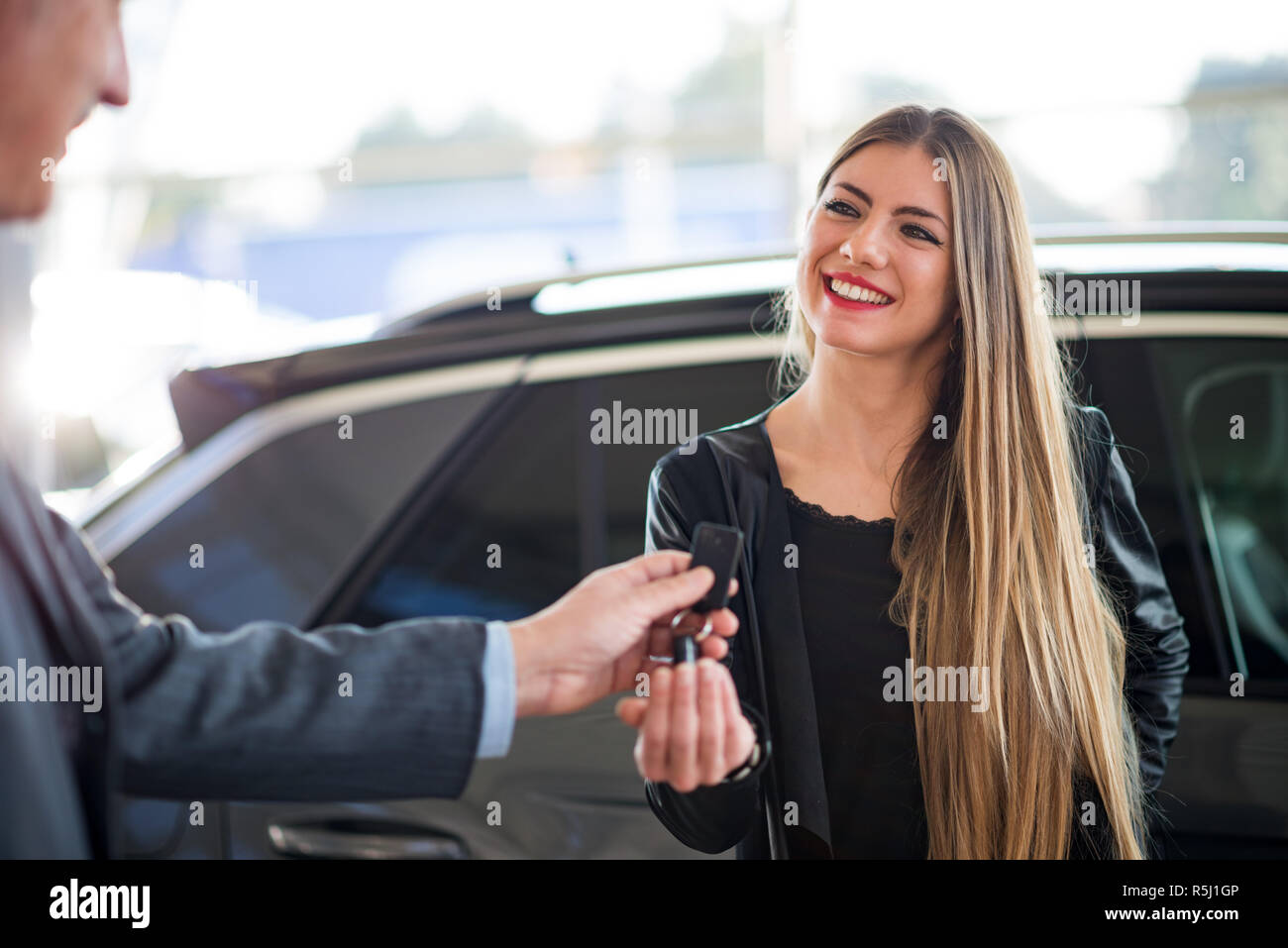 Woman taking the keys for her car in a showroom Stock Photo - Alamy