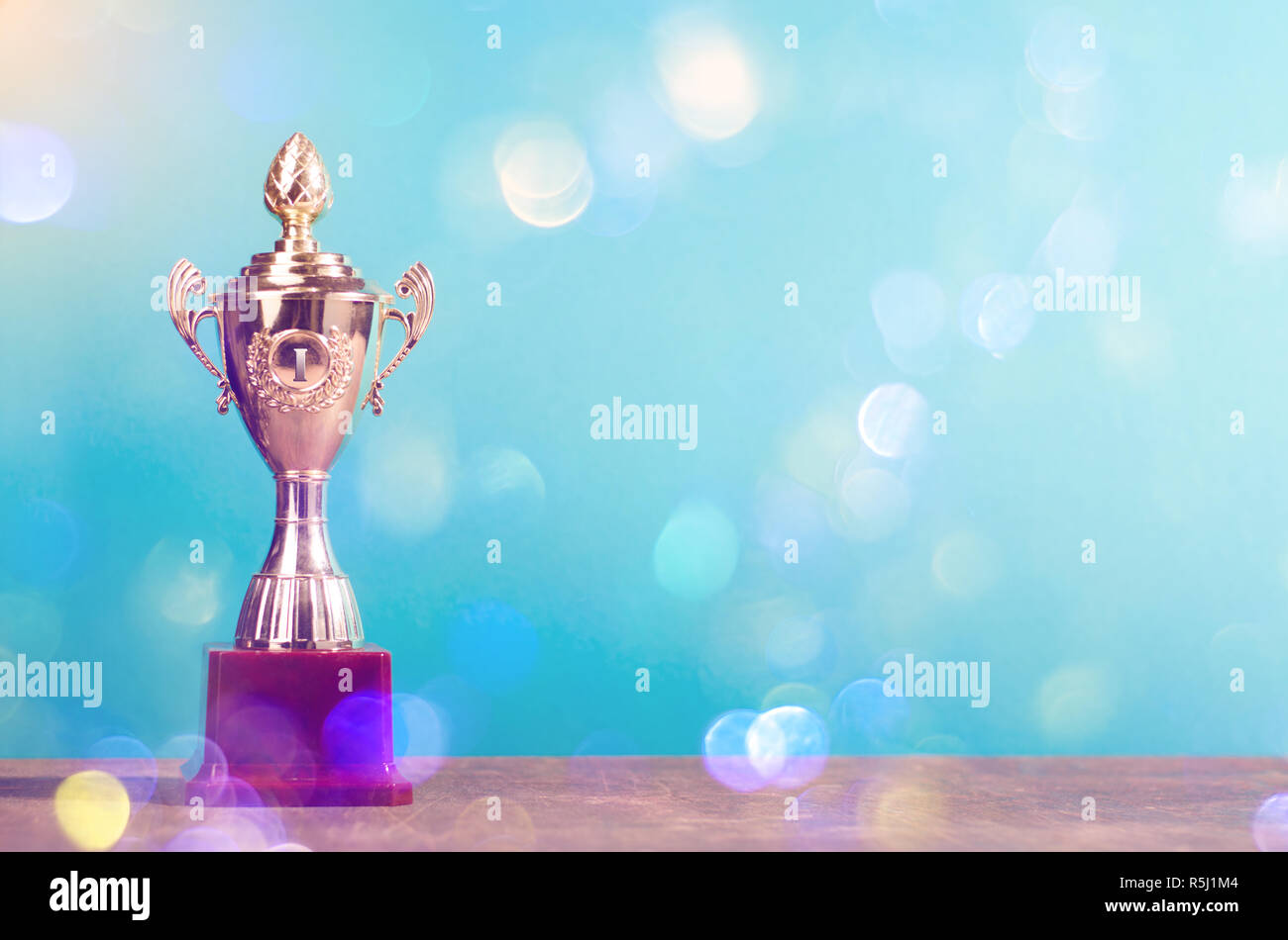 Golden winner's trophy on sky background standing on wooden desk ...