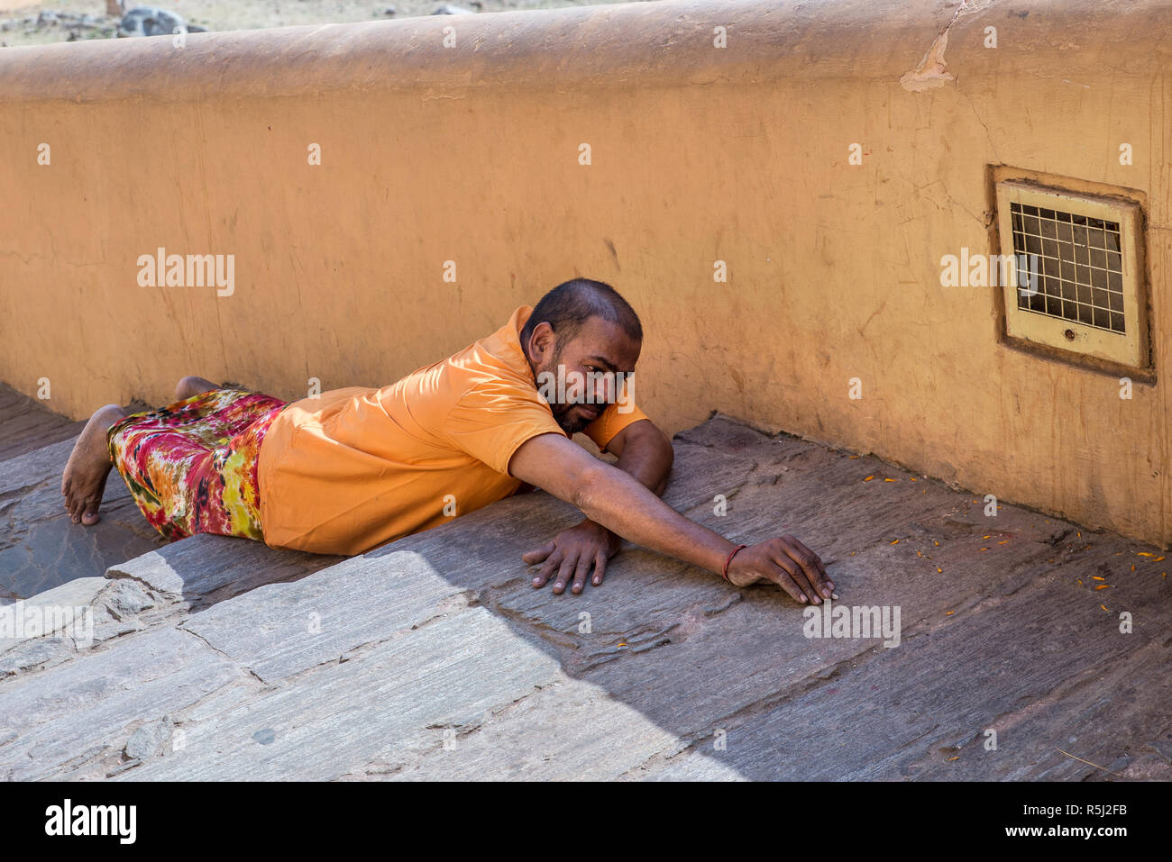 A pilgrim laying down on the stairs to Amber Fort, Amer, Rajasthan ...